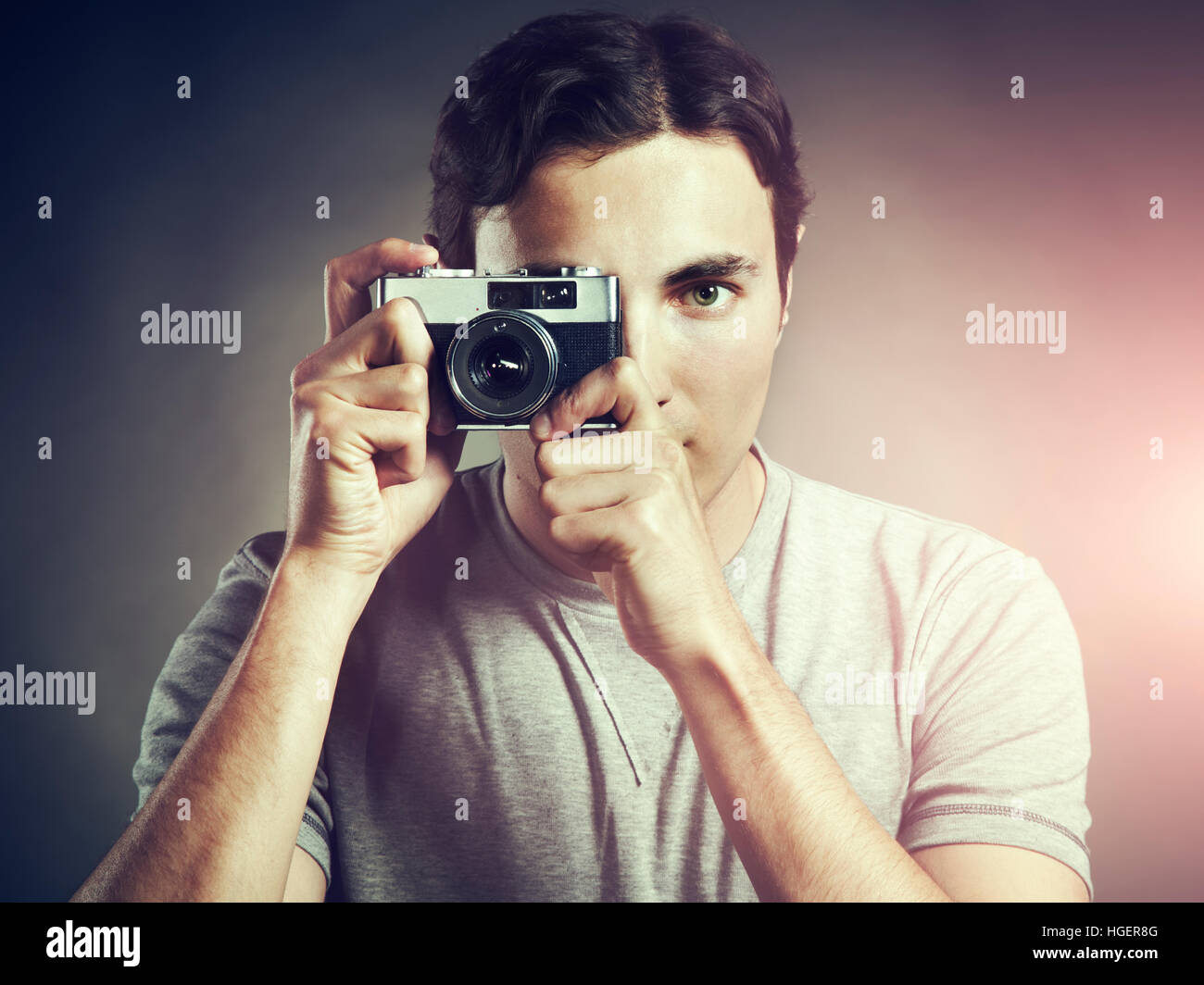 Portrait of young male photographer with a camera. Man shoots at camera ...