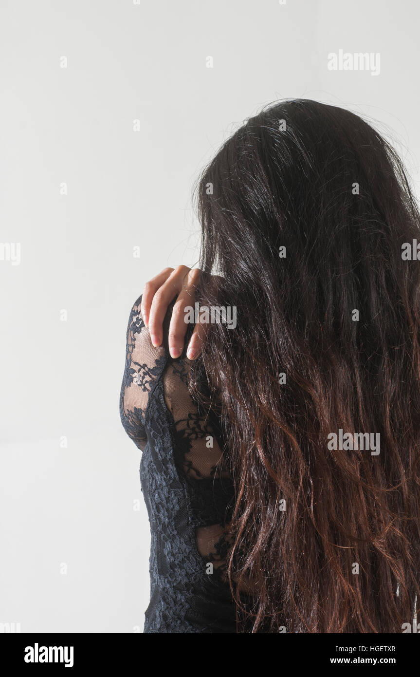 Rear view of a woman with dark hair hand touching shoulder Stock Photo ...