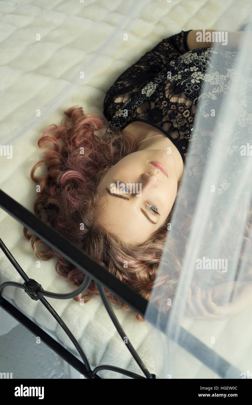 Sad woman laying down in bed Stock Photo - Alamy