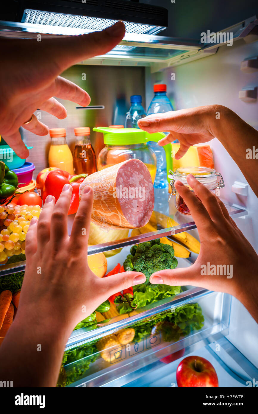 Human hands reaching for food at night in the open refrigerator Stock ...