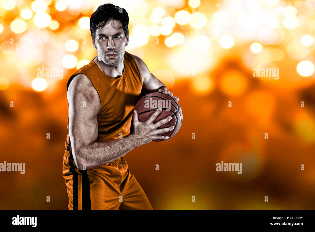 Basketball player on a orange uniform, on a orange lights background ...