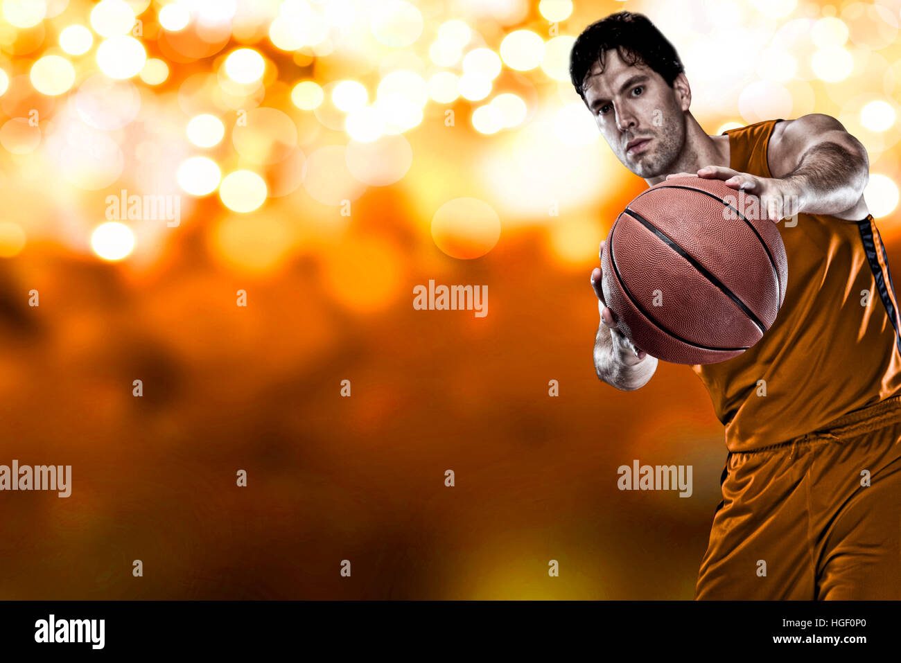 Basketball player on a orange uniform, on a orange lights background ...