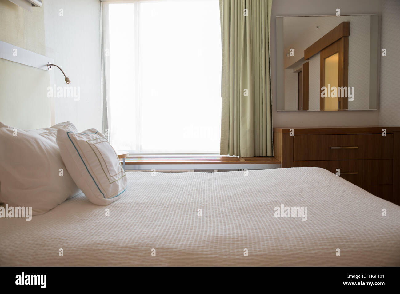 Contemporary hotel bed with morning light from window Stock Photo - Alamy