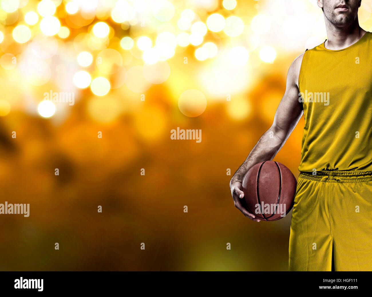 Basketball player on a yellow uniform, on a yellow lights background ...