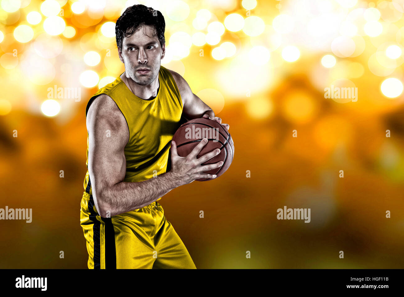 Basketball player on a yellow uniform, on a yellow lights background ...