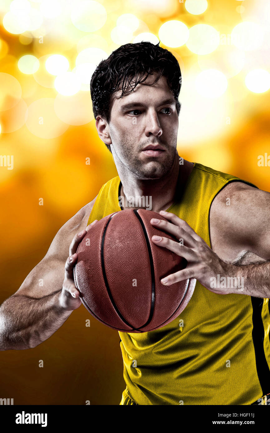 Basketball player on a yellow uniform, on a yellow lights background ...