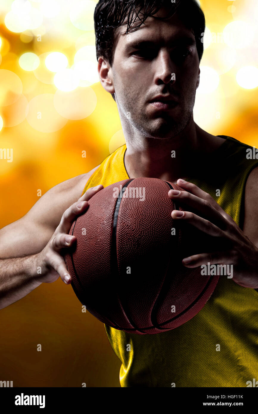 Basketball player on a yellow uniform, on a yellow lights background ...