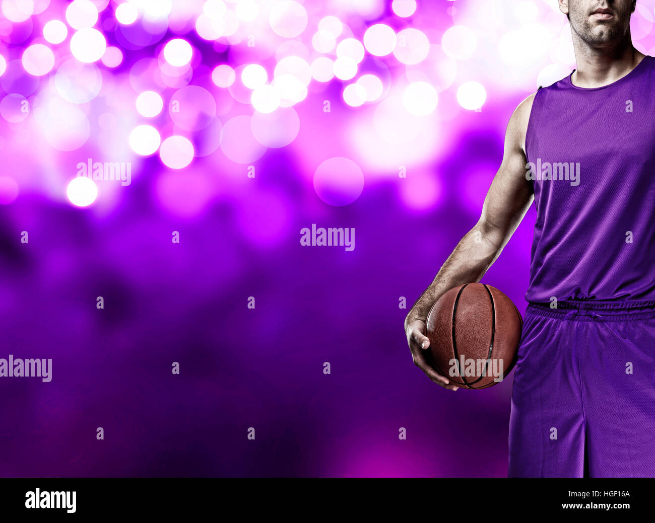 Basketball player on a purple uniform, on a purple lights background ...