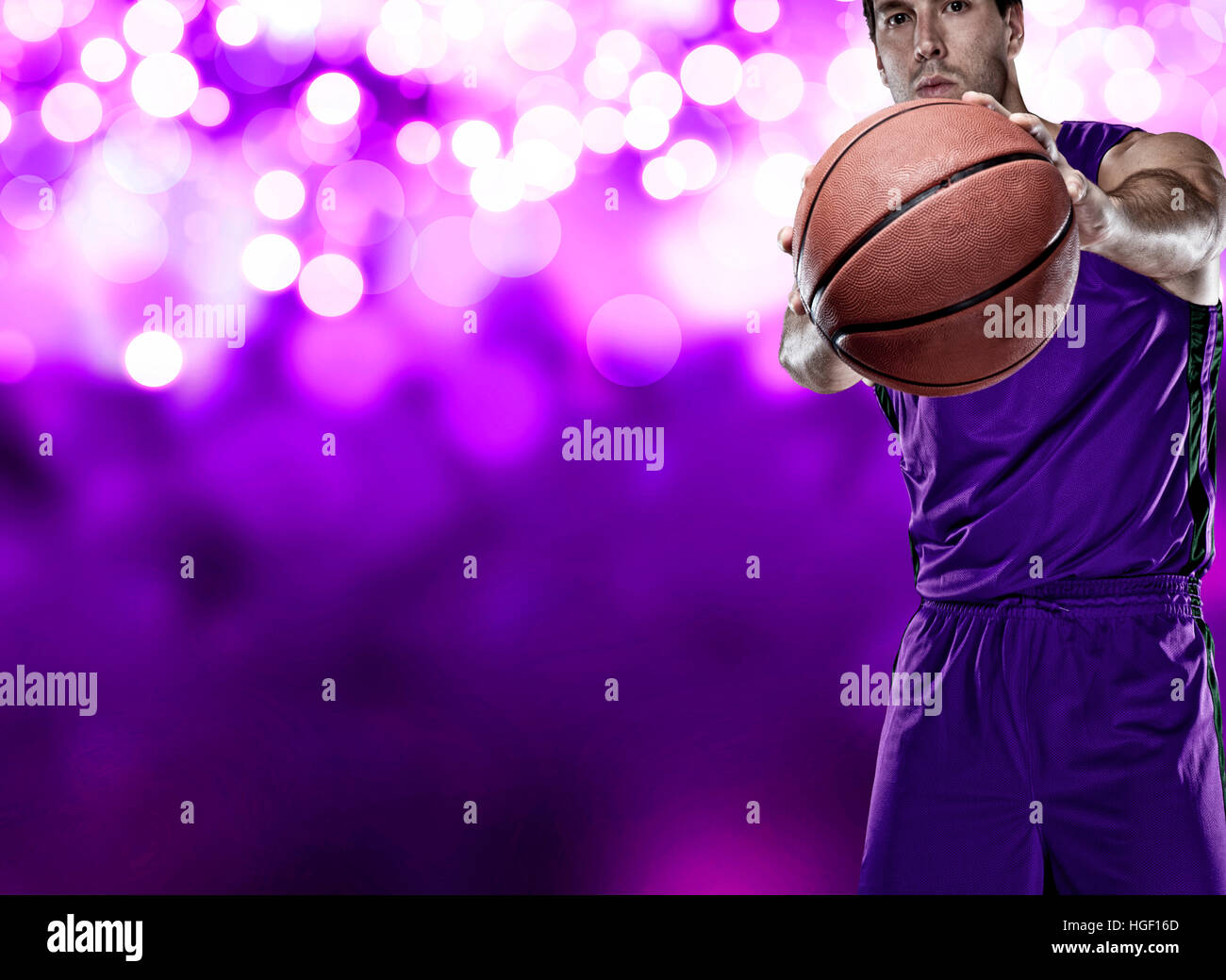 Basketball player on a purple uniform, on a purple lights background ...