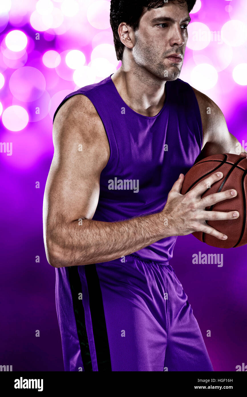 Basketball player on a purple uniform, on a purple lights background ...