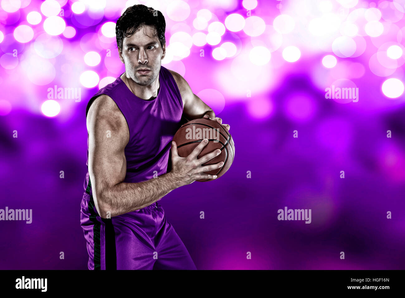 Basketball player on a purple uniform, on a purple lights background ...