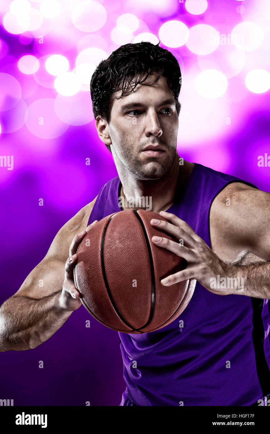 Basketball player on a purple uniform, on a purple lights background ...
