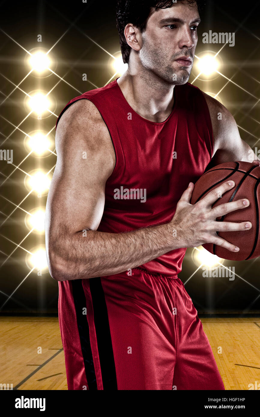 Basketball player on a red uniform, in front of lights Stock Photo - Alamy