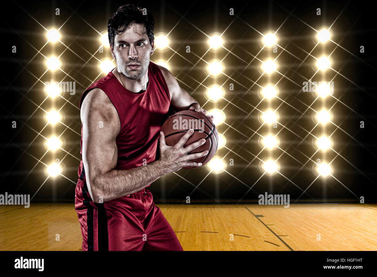 Basketball player on a red uniform, in front of lights Stock Photo - Alamy