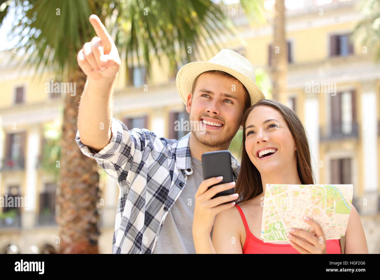 Happy couple of tourists sightseeing and pointing to a landmark in the ...