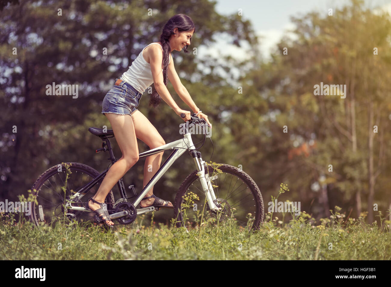 happy slim girl biking in summer park, toned image Stock Photo - Alamy
