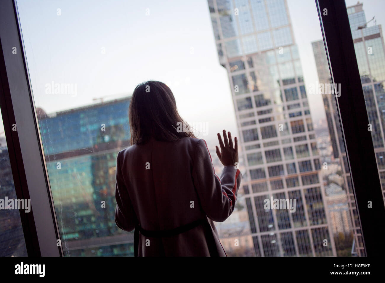 Back view woman looking at the city. Watching cityscape from skyscraper ...
