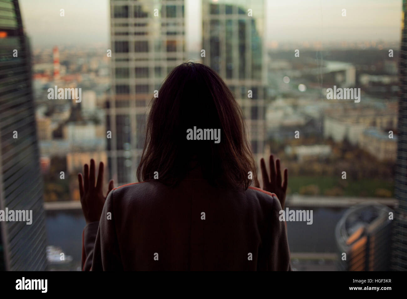 Back view woman looking at the city. Watching cityscape from skyscraper ...