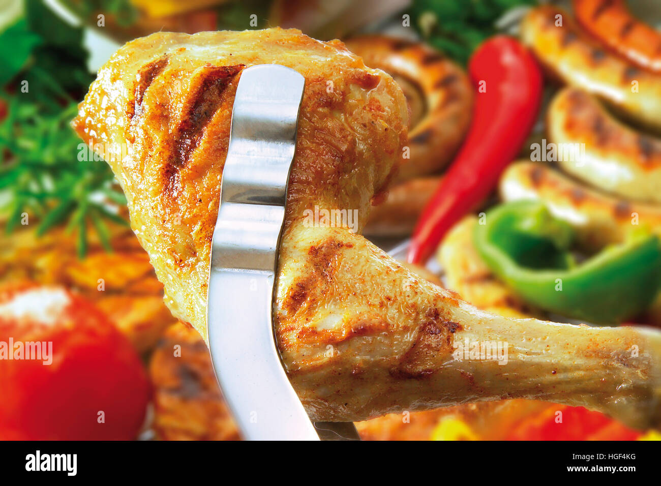 Barbecue tongs holding chicken drumstick Stock Photo - Alamy