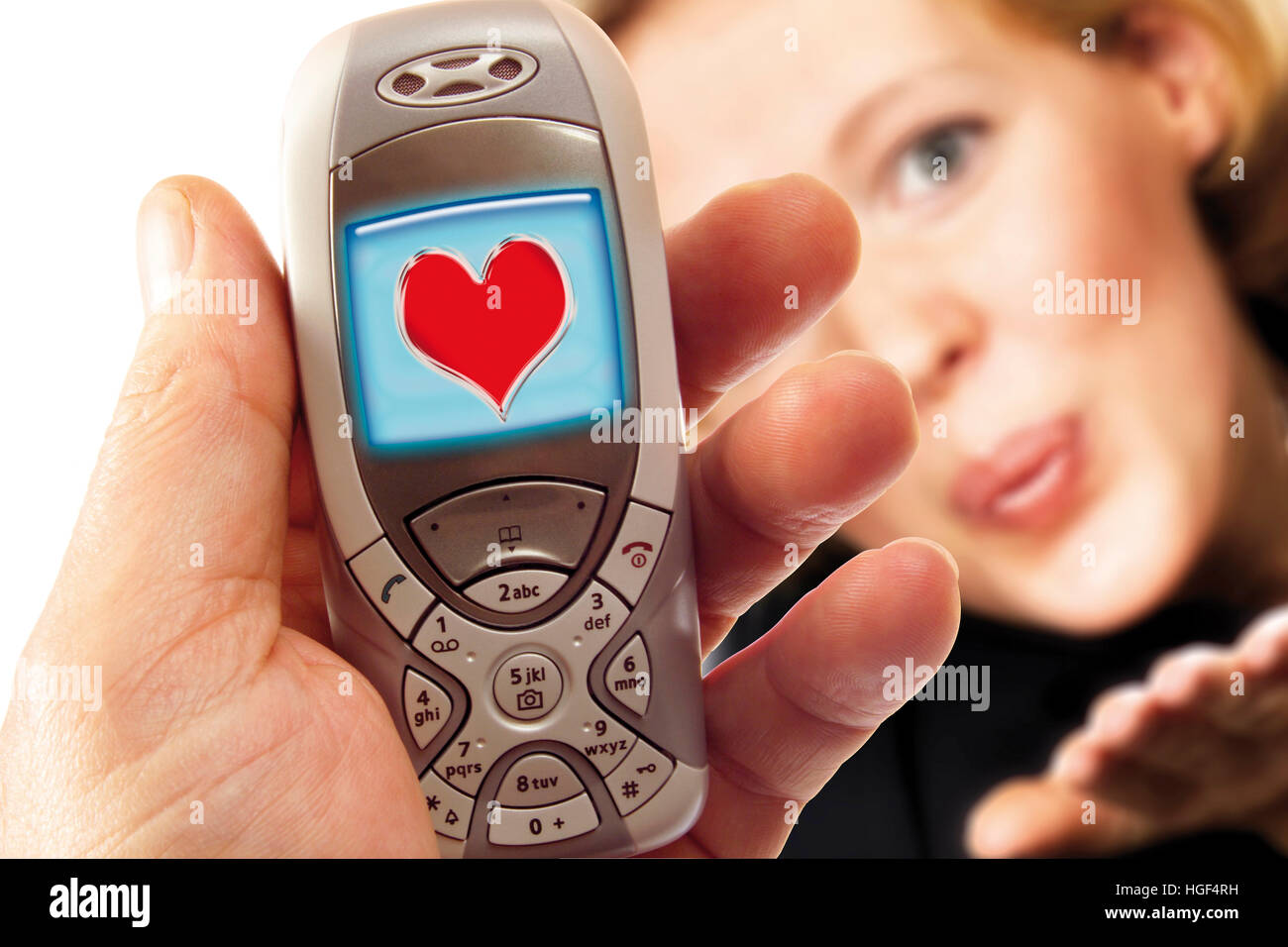 Hand holding a mobile phone with heart-shaped logo display, young woman ...