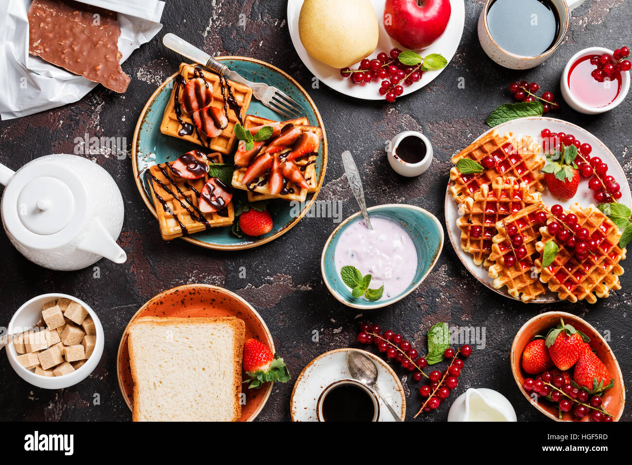 Breakfast table with waffles, yogurt, coffee and fresh fruits and ...