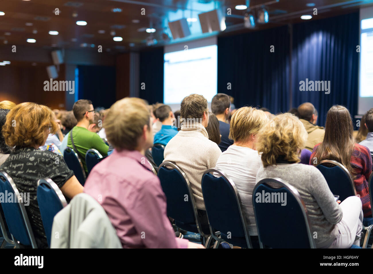 Audience in lecture hall participating at business event Stock Photo ...