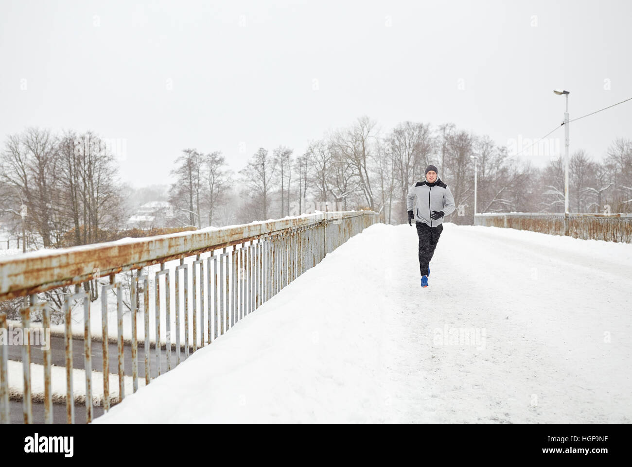 man running along snow covered winter bridge road Stock Photo - Alamy