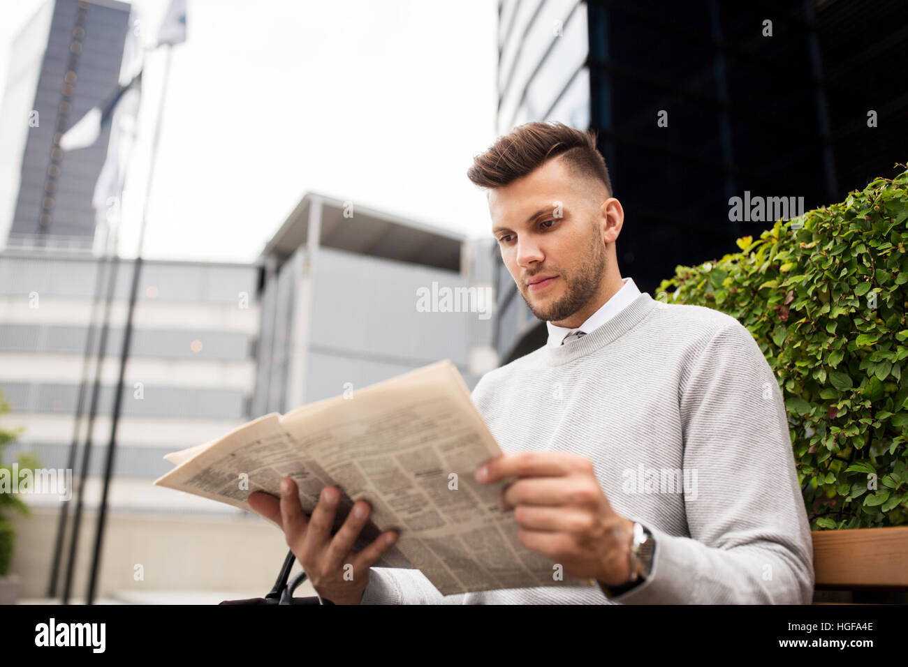 man reading newspaper on city street bench Stock Photo - Alamy