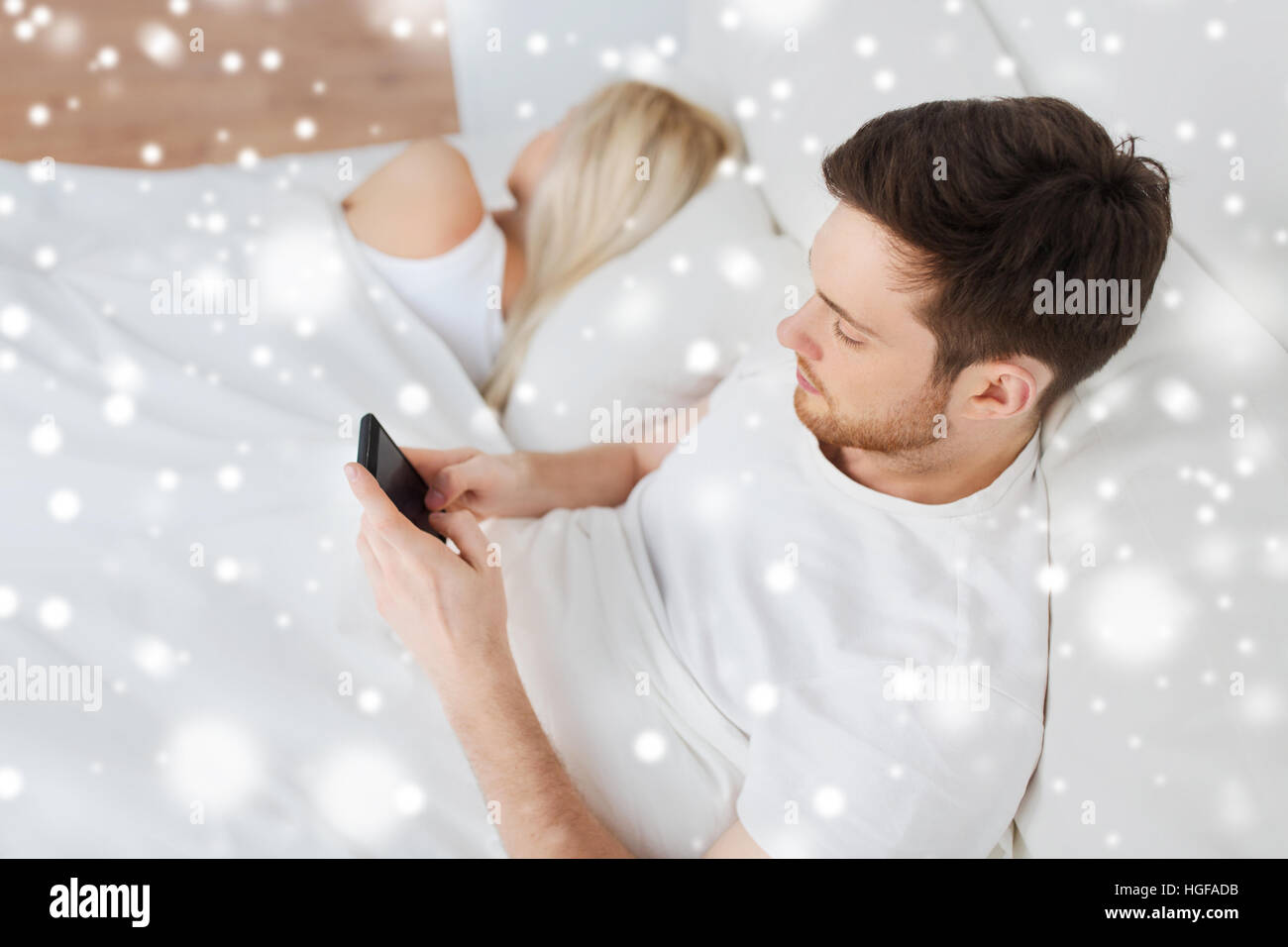 man texting message while woman is sleeping in bed Stock Photo - Alamy