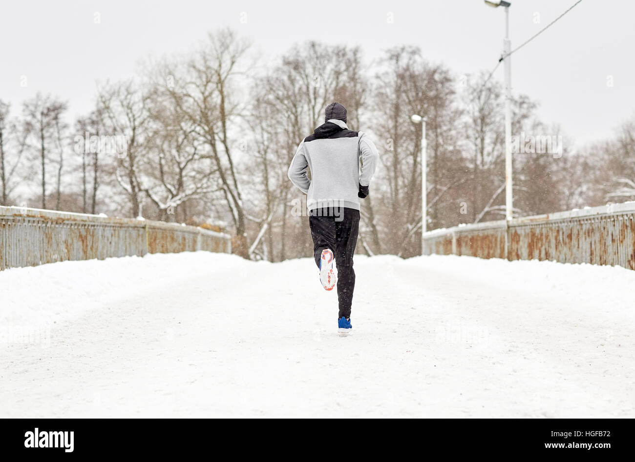 man running along snow covered winter bridge road Stock Photo - Alamy