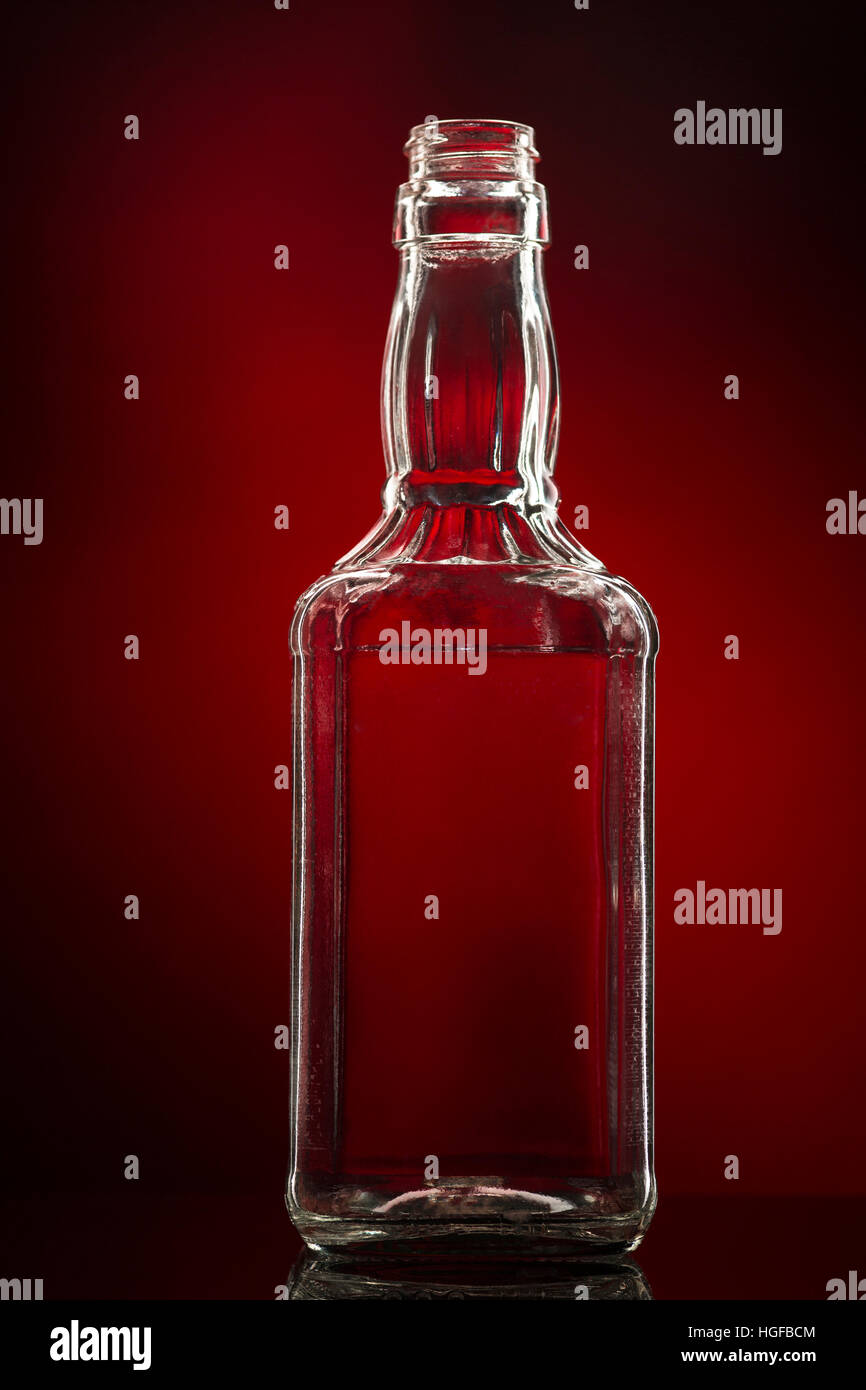 Empty colorless glass bottle on red background Stock Photo - Alamy