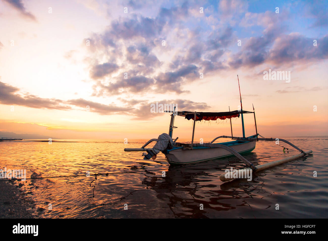 sunset on the beach in Bali, traditional fisherman boat in Indonesia ...