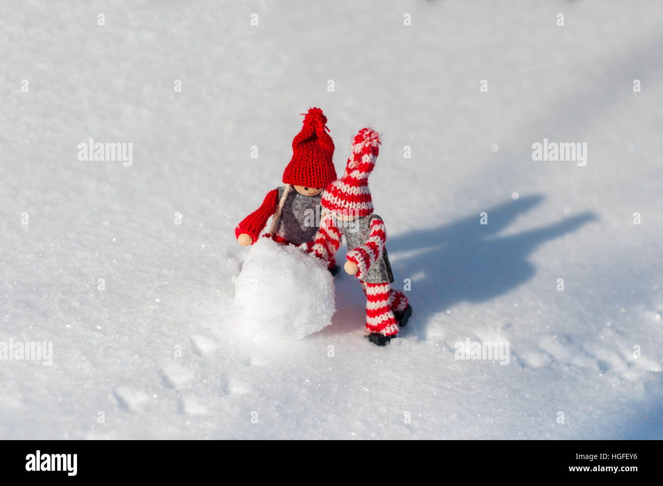 Two toy little man rolled a snowball, sunny day Stock Photo - Alamy