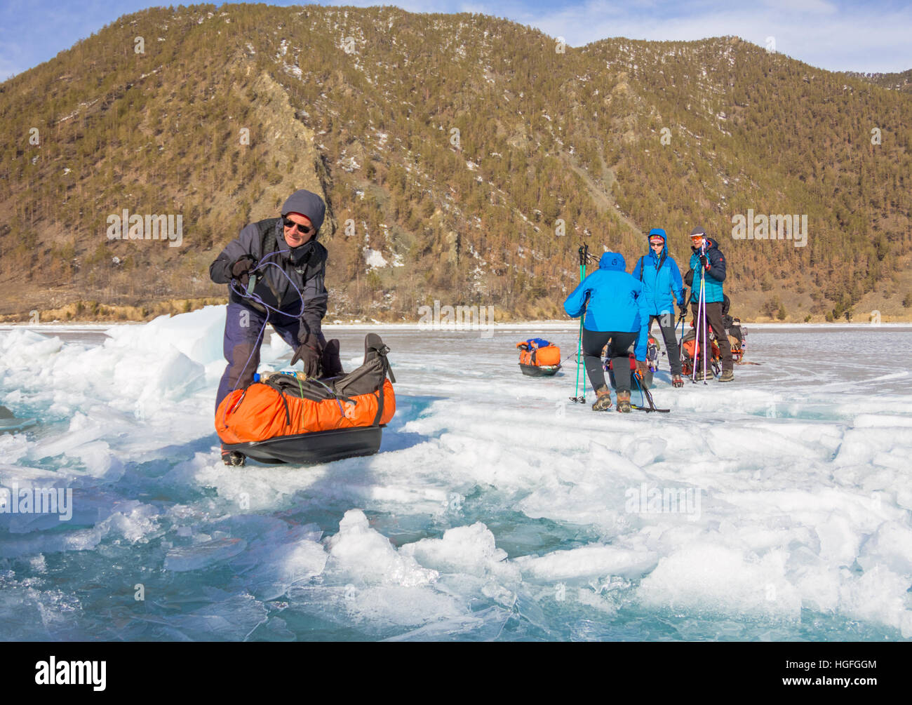 Lake Baikal, Russia - March 24, 2016: The men dragged the ice sledge ...