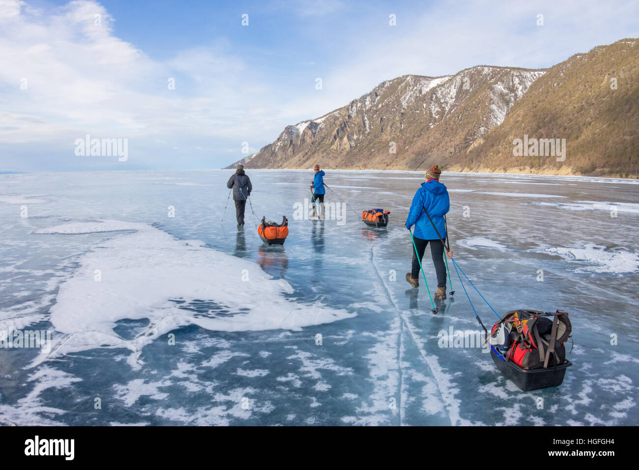 woman and a man with a sledge and trekking pole is ice of Baikal Stock ...
