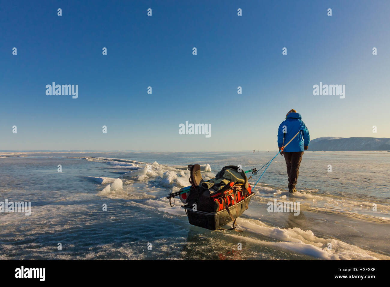 Girl with a sledge and trekking pole is on the ice of Lake Baikal Stock ...