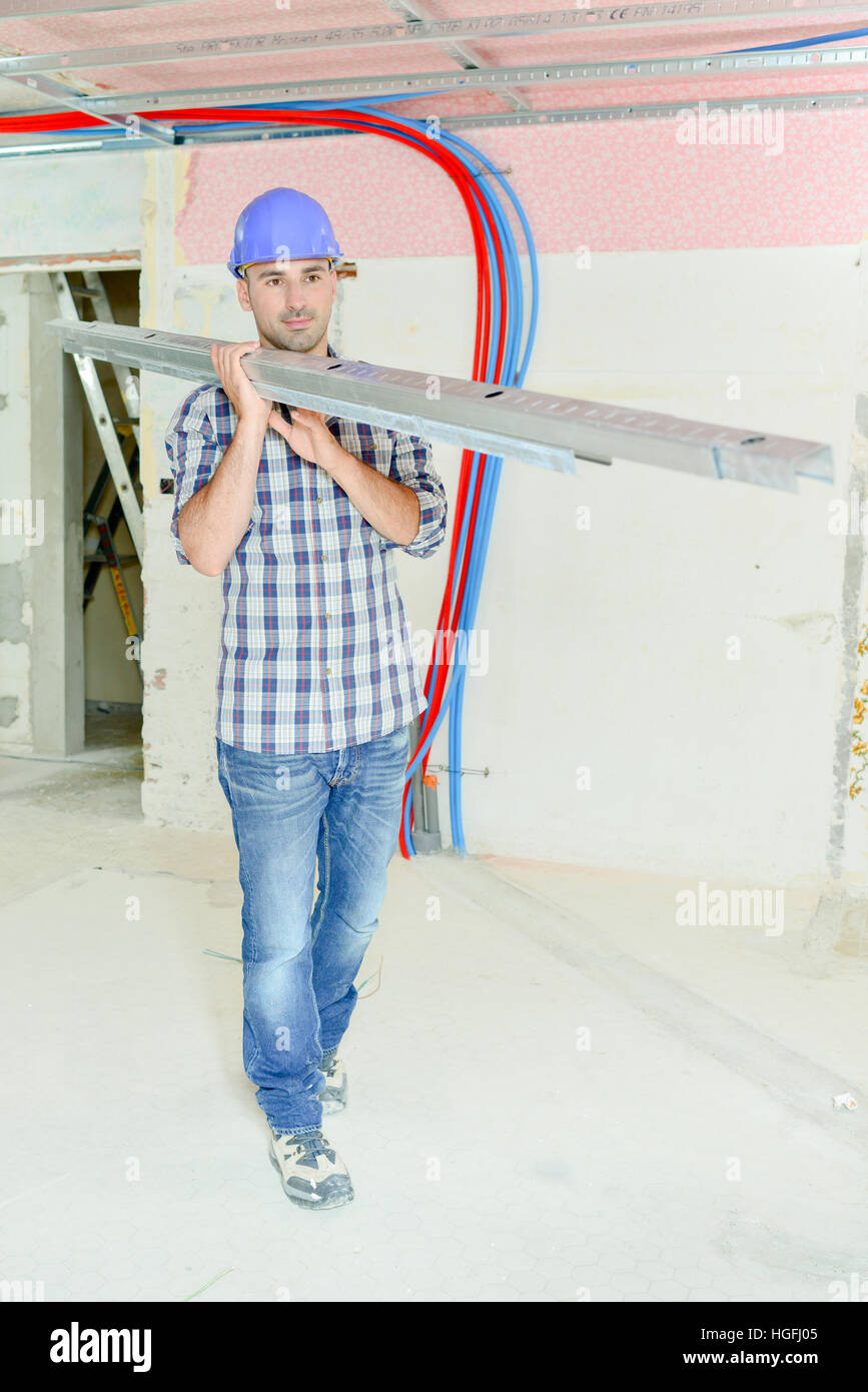 Builder carrying metal joists Stock Photo - Alamy