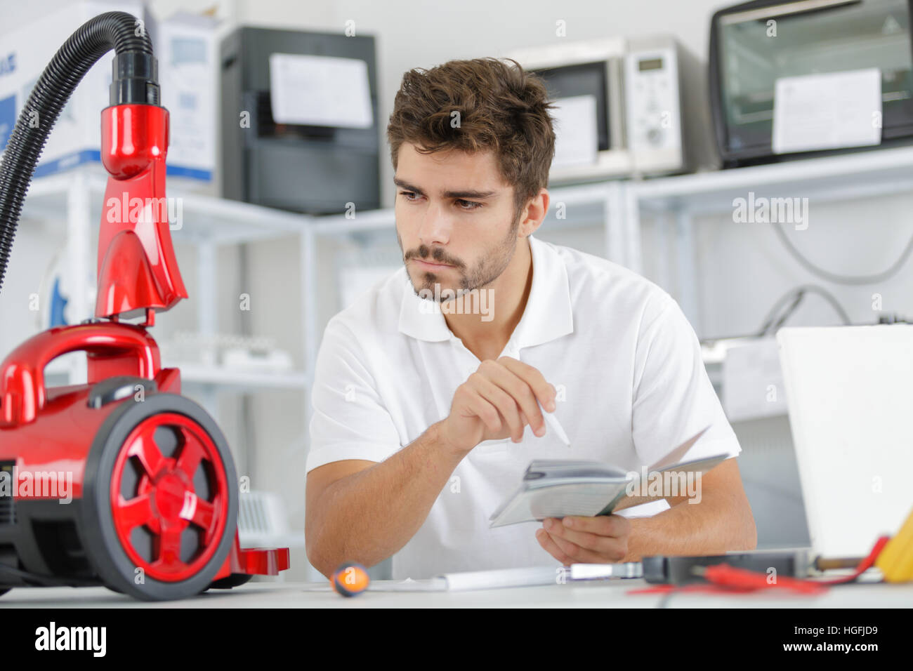 repairman diagnosing vacuum cleaner in his workshop Stock Photo - Alamy