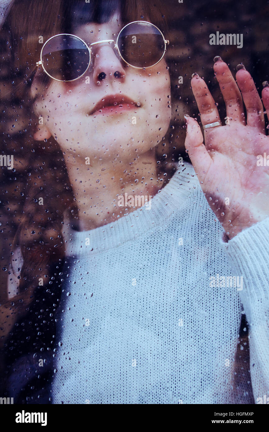 Portrait of a young woman in a rainy day through a window Stock Photo ...