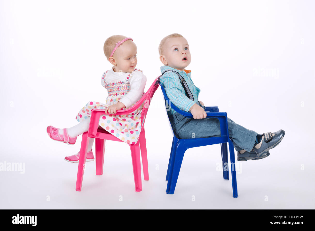 funny boy and girl sitting on chairs back to back Stock Photo - Alamy