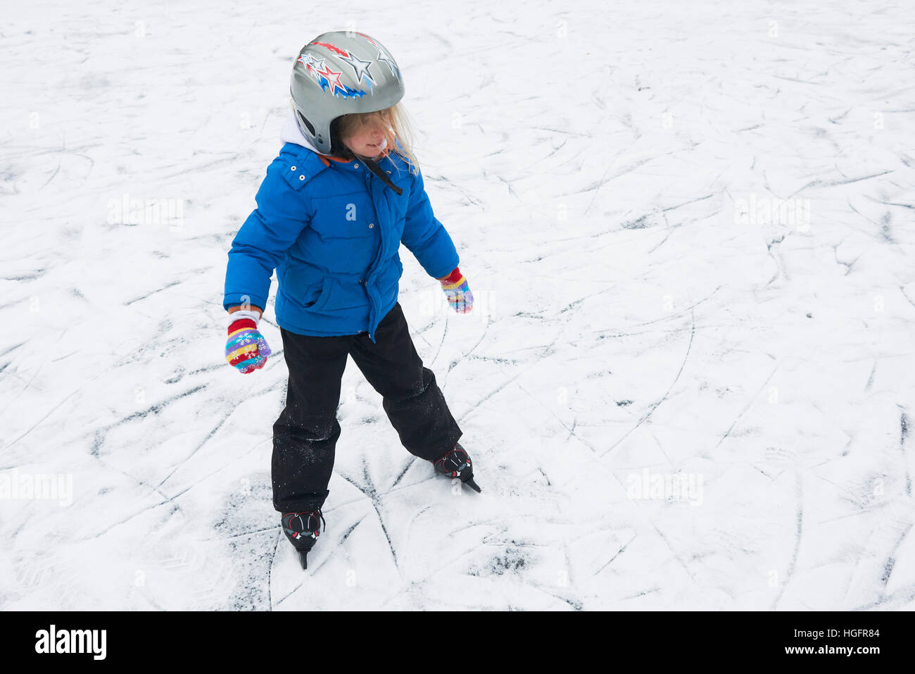 Adorable little child girl ice skating in winter snow day outdoors in ...