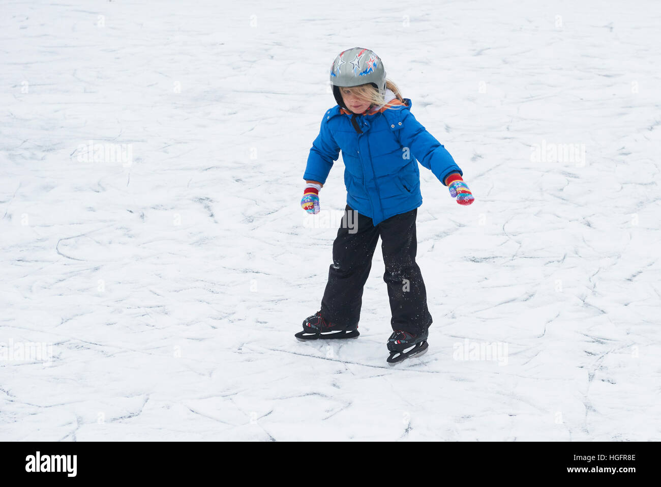 Adorable little child girl ice skating in winter snow day outdoors in ...