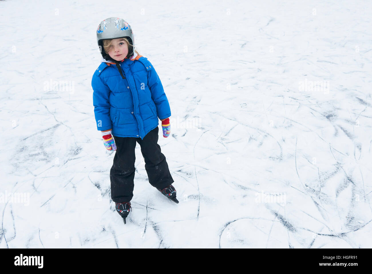 Adorable little child girl ice skating in winter snow day outdoors in ...