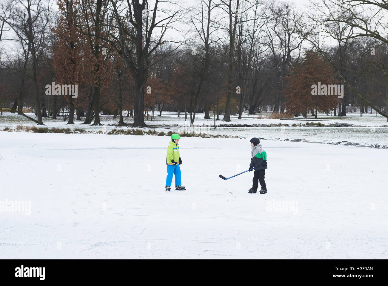 A group of children playing ice hockey at the skating rink outside in ...
