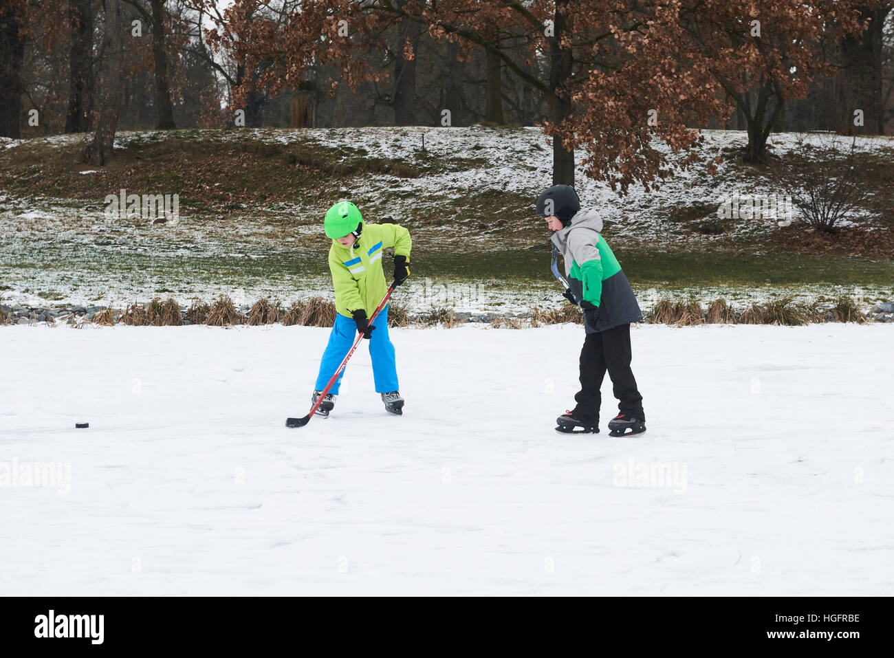 A group of children playing ice hockey at the skating rink outside in ...