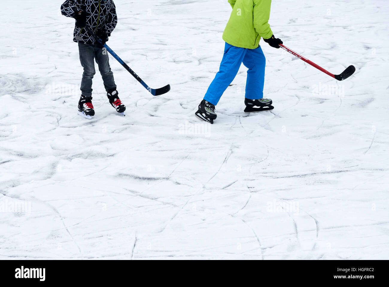 A group of children playing ice hockey at the skating rink outside in ...