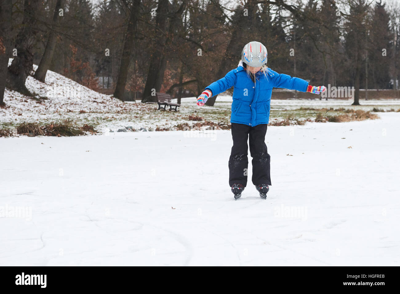 Adorable little child girl ice skating in winter snow day outdoors in ...