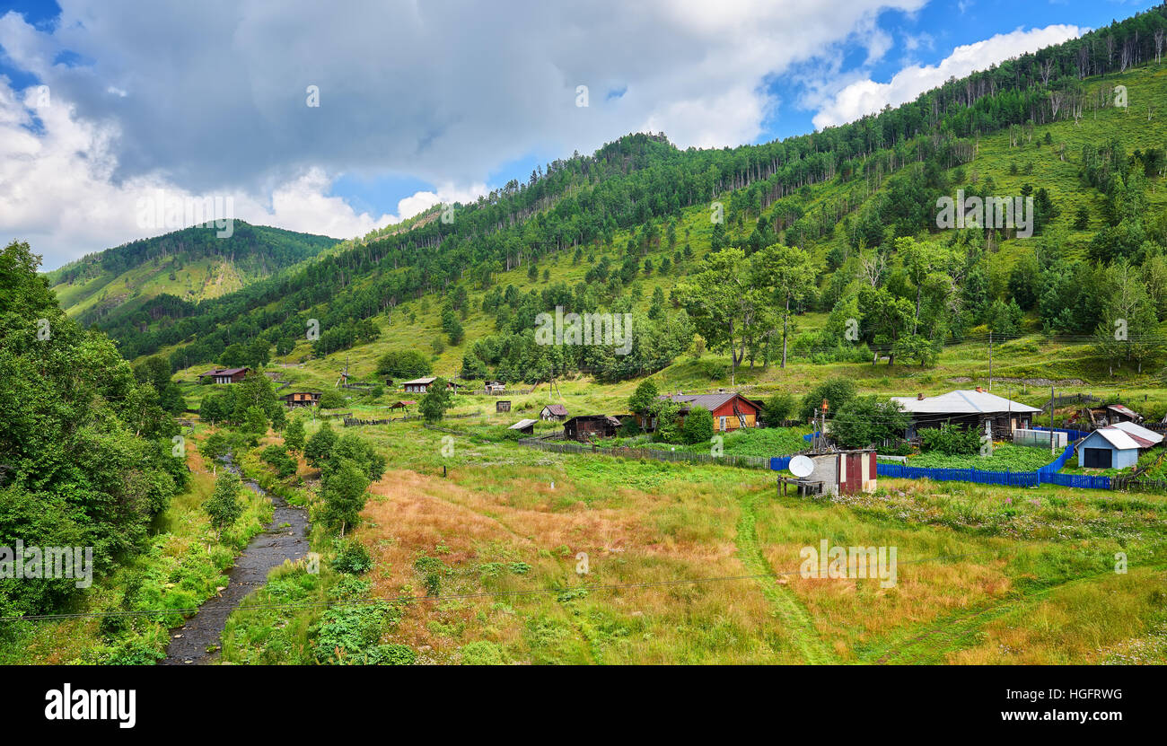 Old wooden houses with gardens in valley of a small stream. Village ...