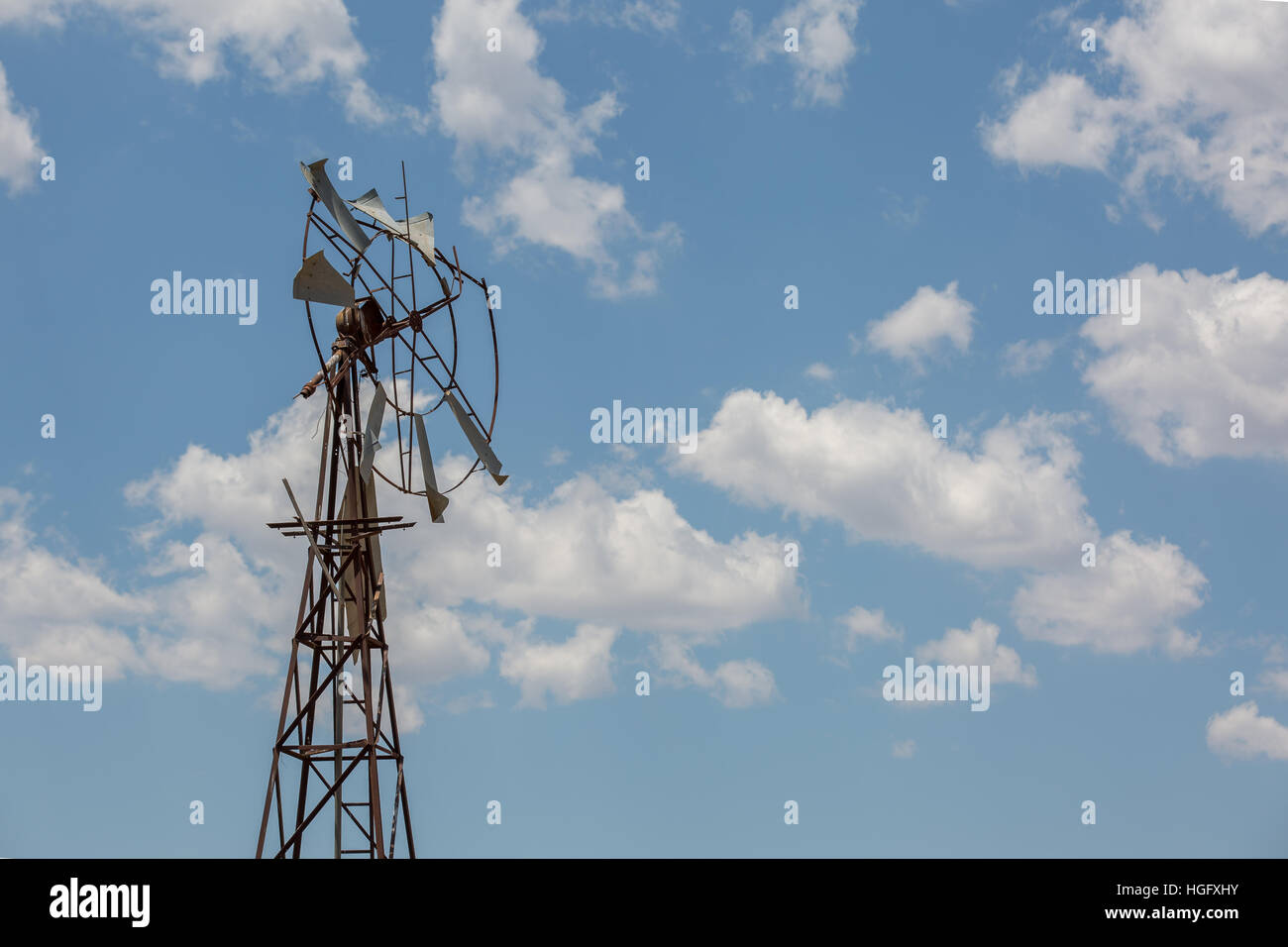 An old, broken and rusted windmill with blue sky and clouds in the ...
