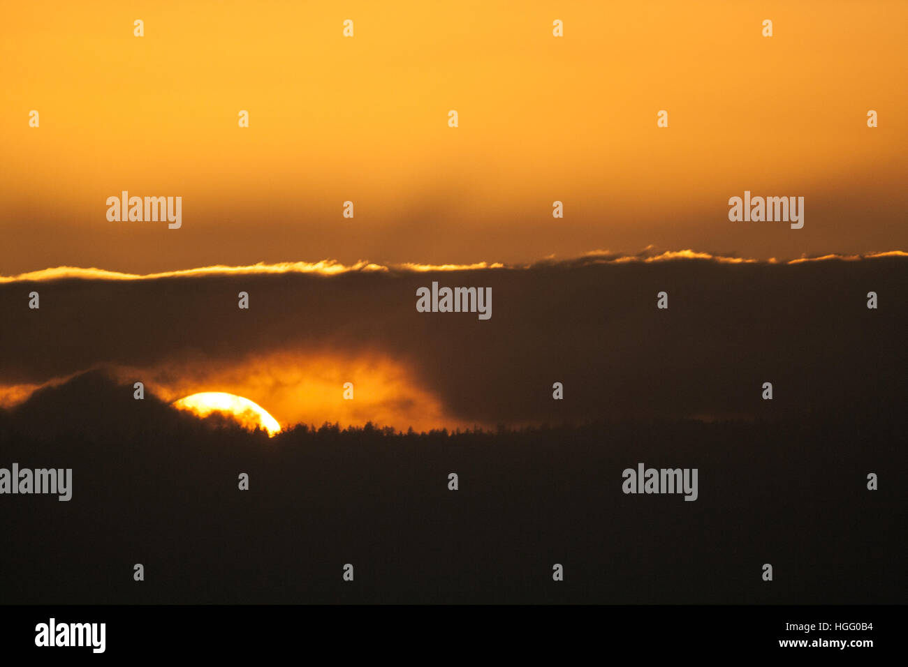 Sunset behind mountains and clouds Stock Photo - Alamy